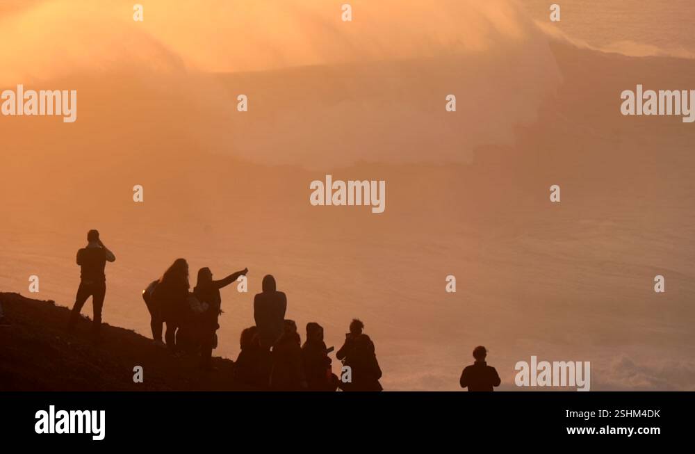 Big crowd people watching giant waves in Nazaré during epic sunset ...