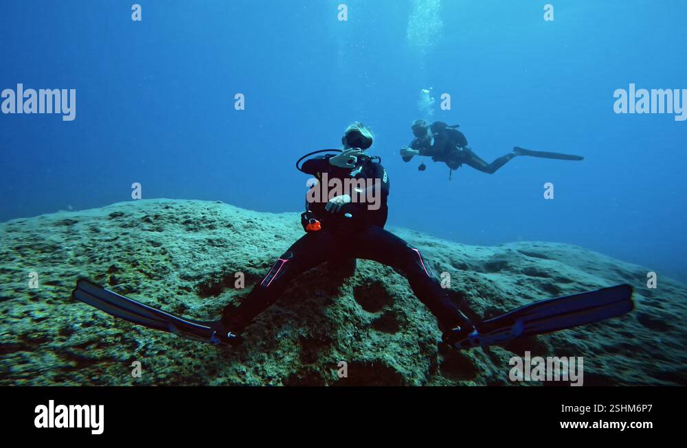 Female diver doing OK sign at camera with male scuba diver behind ...