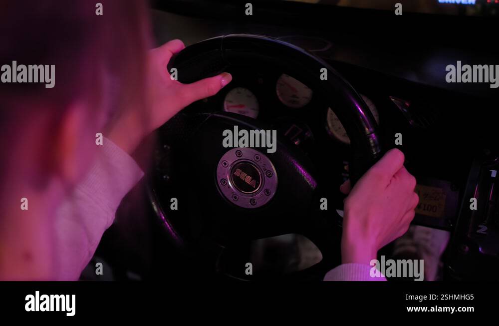 Woman using gaming steering wheel joystick at retro arcade hall: close ...