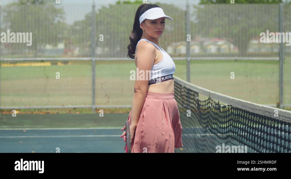 Hispanic girl holds a tennis racket behind her back with the wind ...