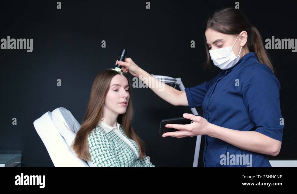 A trichologist examines the patient's hair with a trichoscope in the ...