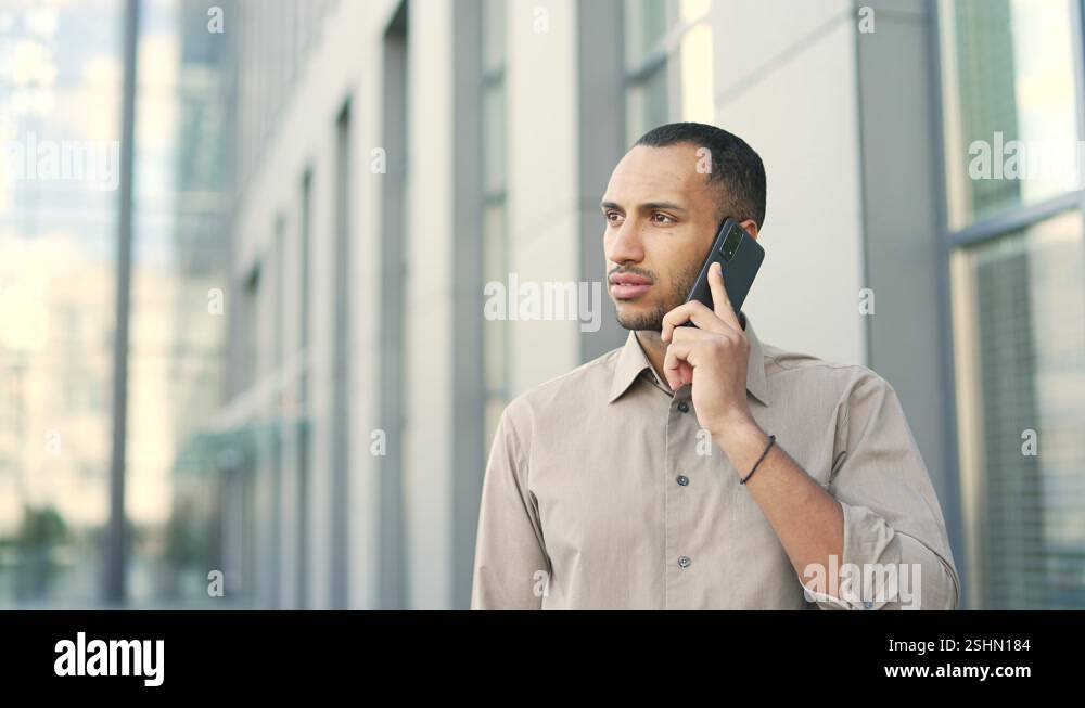 Close up. Young calm businessman talking on a smartphone while standing ...