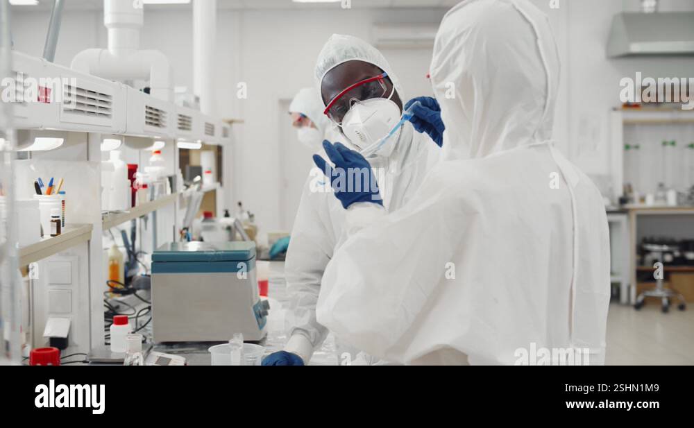 Medicine scientists wearing ppe pouring liquid in test tube dish ...