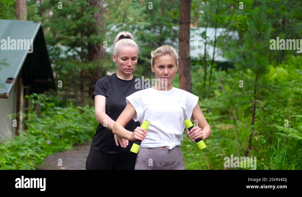 Fitness. Personal trainer taking notes while woman exercising outdoors ...
