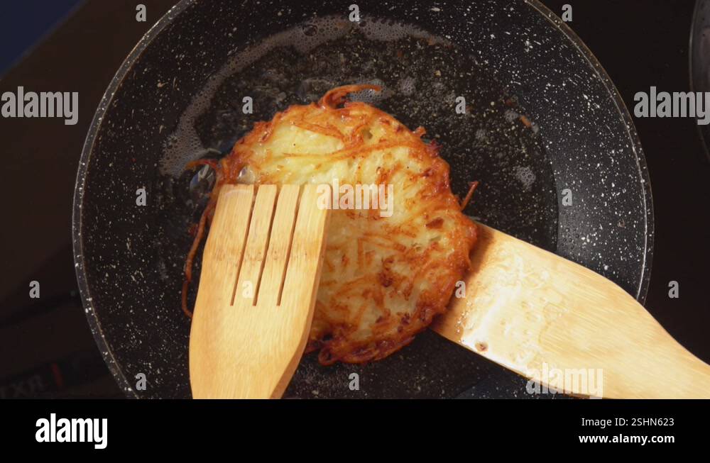 A wooden spatula flips a potato pancake with a crispy crust Stock Video ...