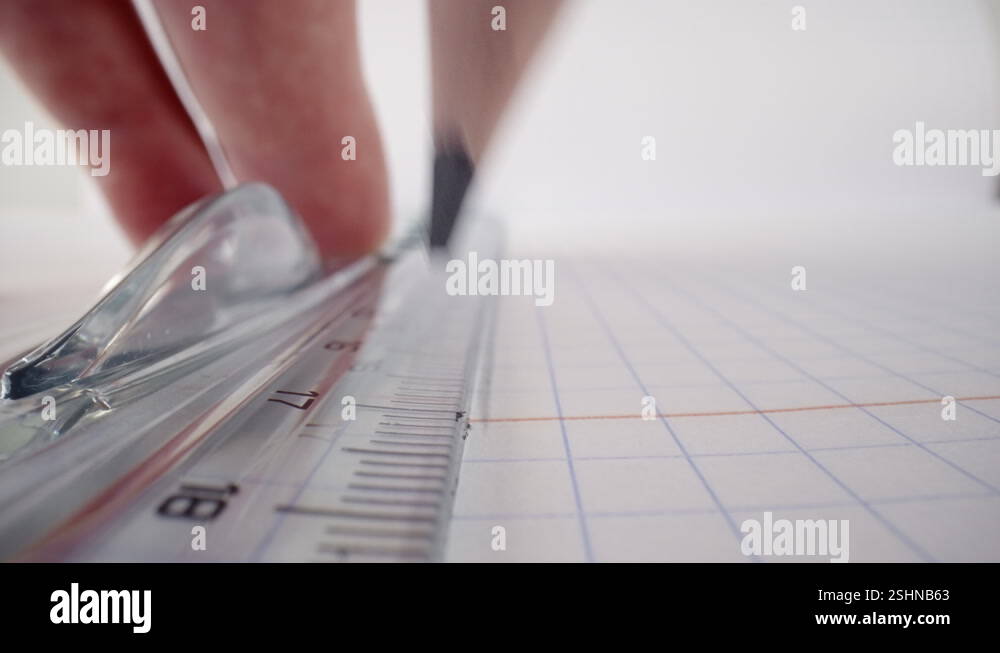 Macro drawing straight line with pencil and ruler on white paper ...
