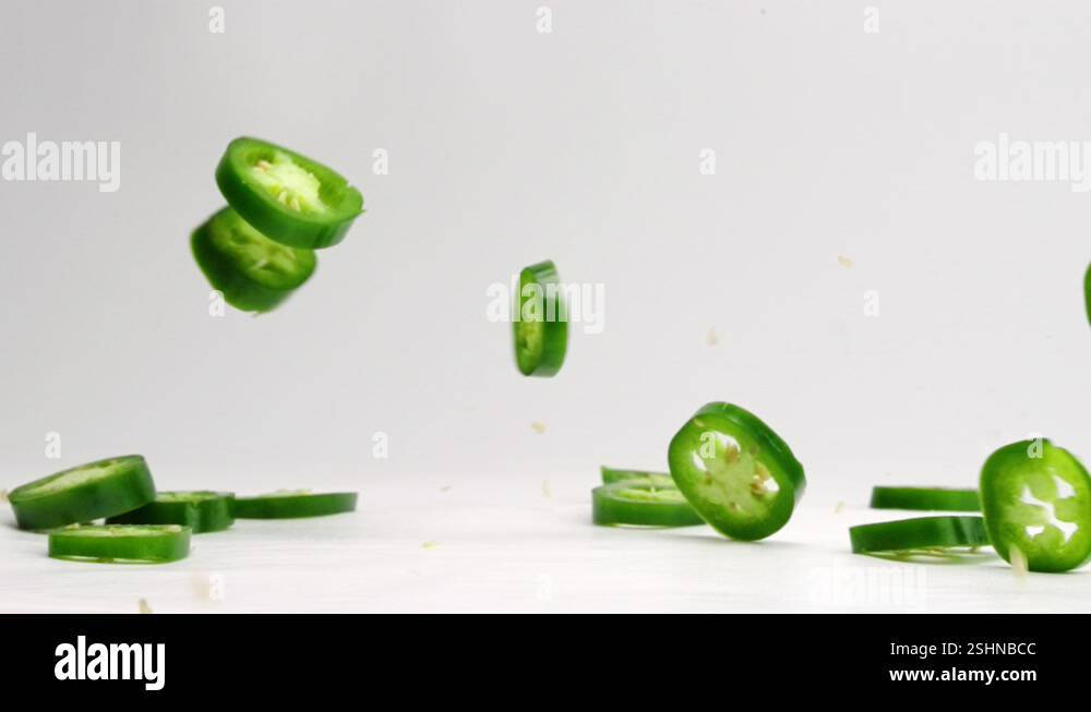 Sliced jalapeño coins falling and bouncing on white studio backdrop in ...