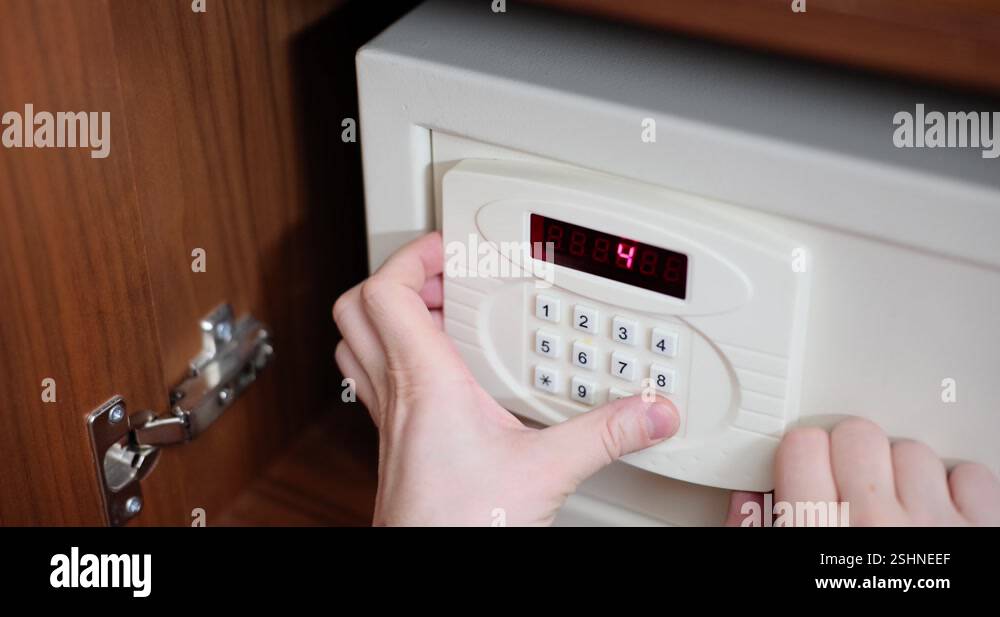 Male hand typing password on door of metal safe on door in hotel ...