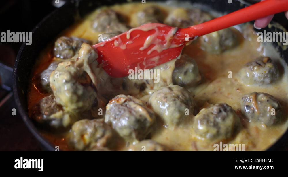 Chef stirring meatballs in creamy sauce with plastic spatula closeup 4k ...