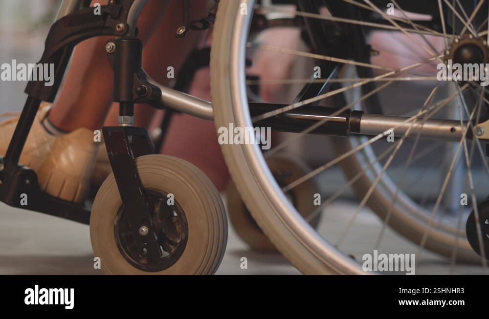 Legs of female patient with disability moving in wheelchair in room ...