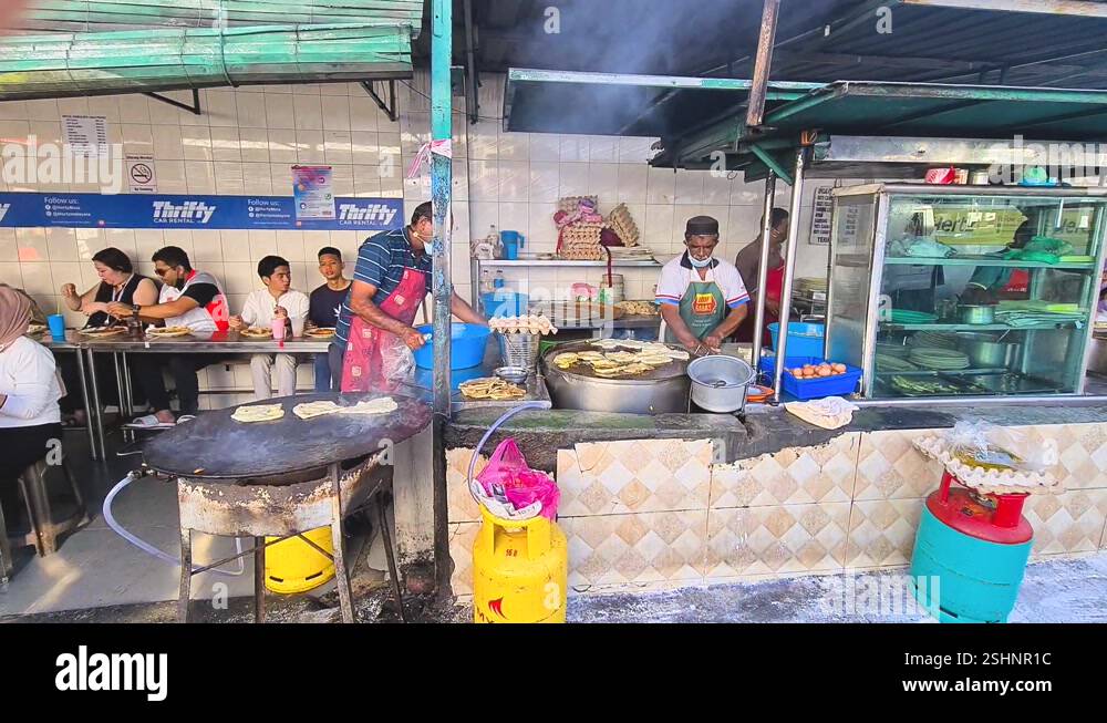 Two men preparing food for people eating at a roadside restaurant Stock ...