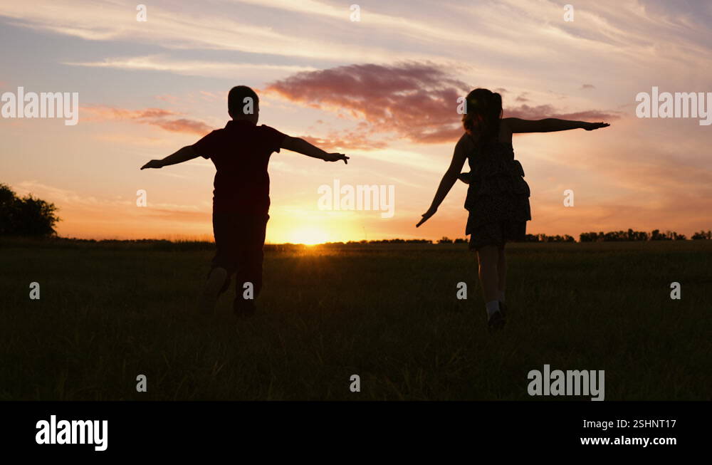 Boy, girl aviators run with their hands raised like an airplane across ...