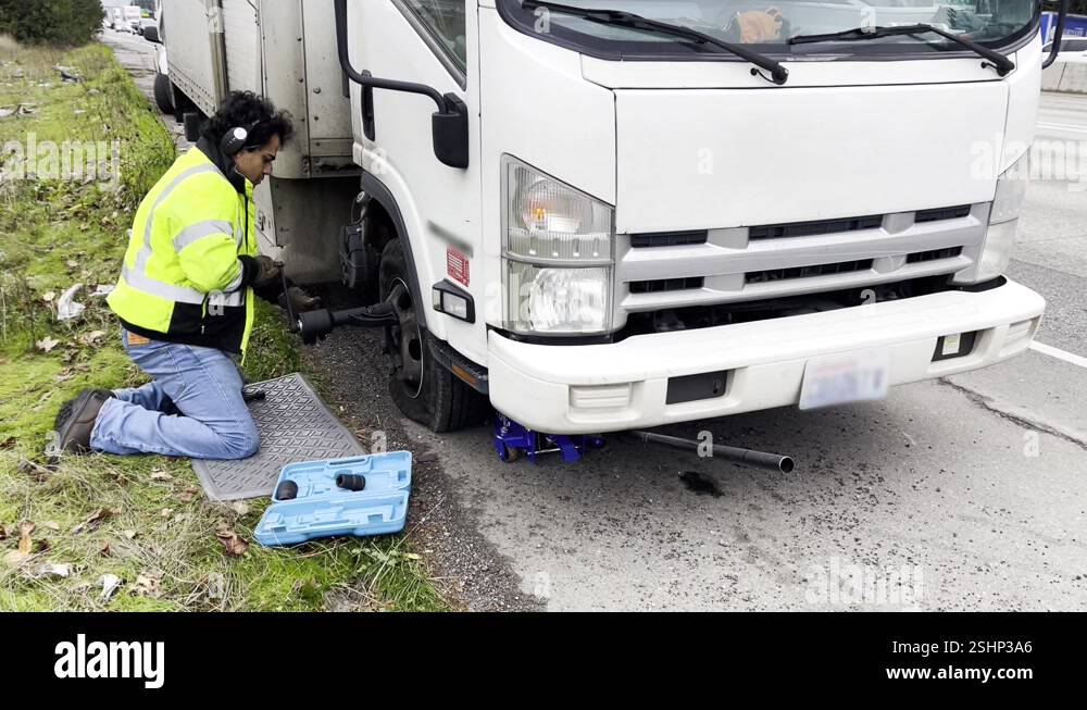 Mexican man changing the tire of a trailer stranded on the road ...