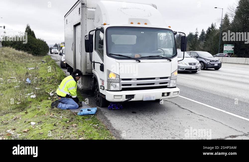 Changing the tire of a trailer stranded on the road. Immigrant works ...