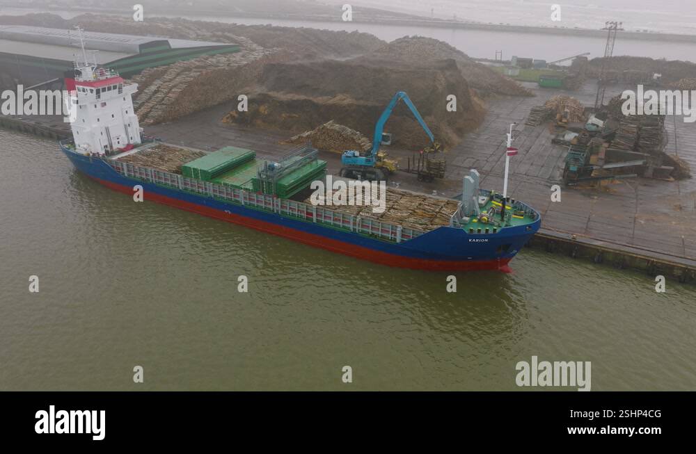 Aerial establishing view of wood terminal crane loading timber into the ...