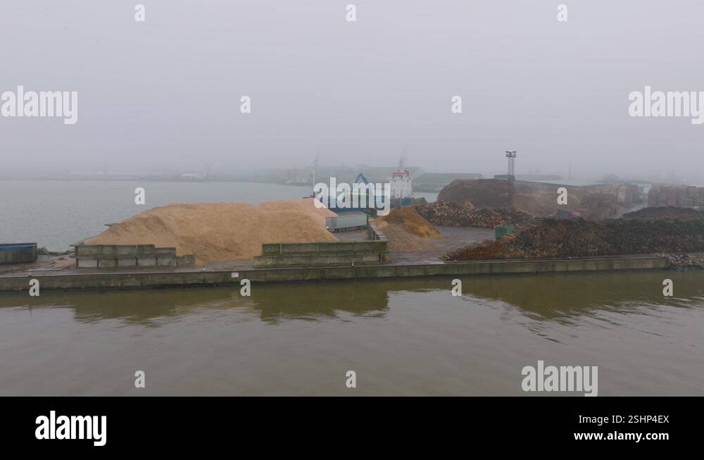 Aerial establishing view of wood terminal crane loading timber into the ...
