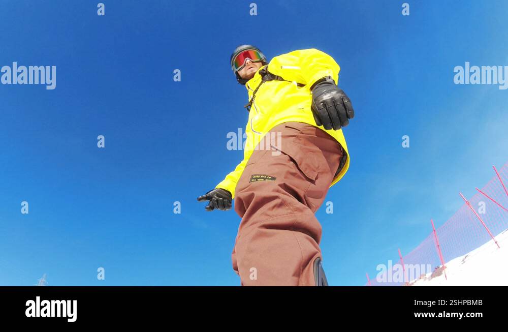 Bottom view of a young man riding a snowboard. Snowboarder carving on ...