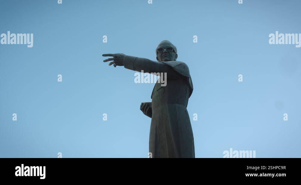 Low perspective camera shot of a statue of a priest who is pointing in ...