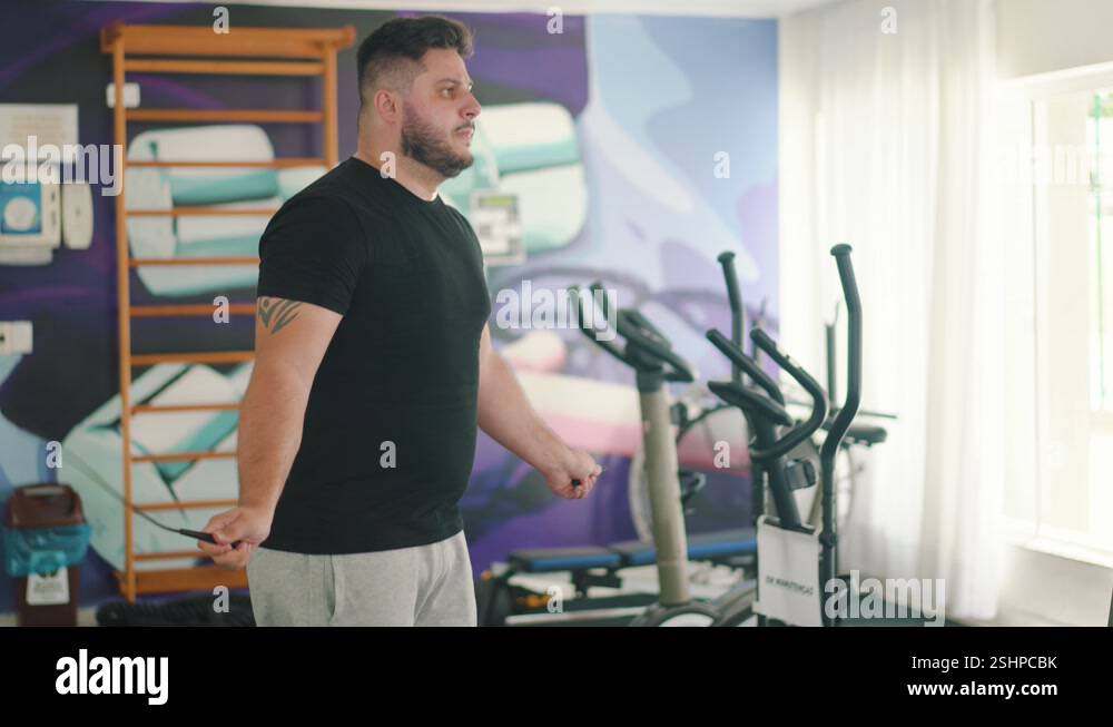 Strong young man using a jumping rope to improve muscle strength and ...