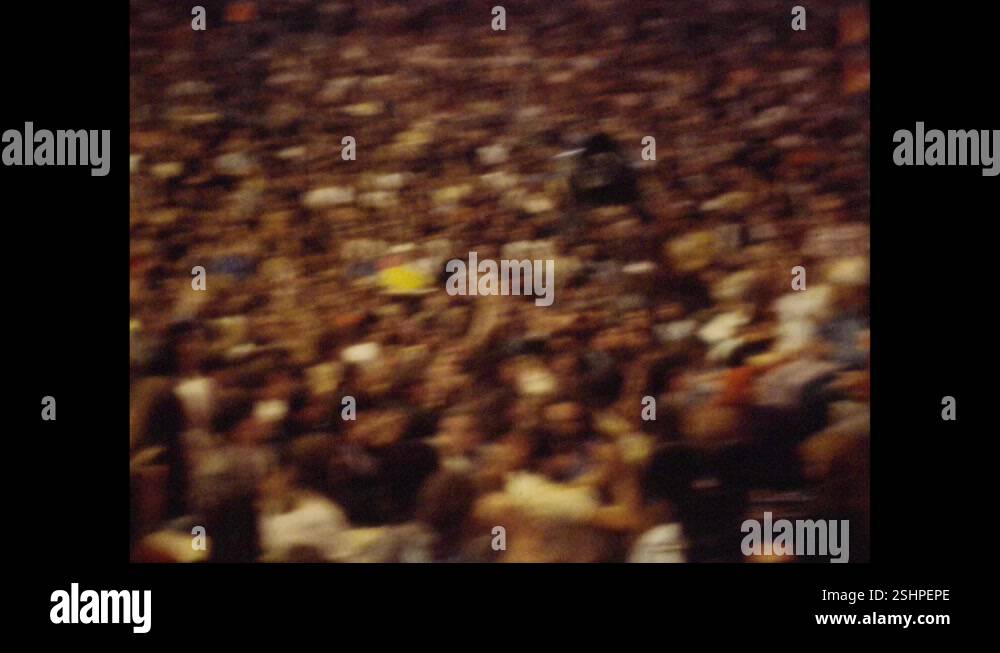 1960s: Huge crowd listening to speakers. Guys sitting behind table ...