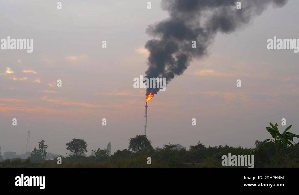 thick Smoke and bright flame shoot out the top of a large industrial ...