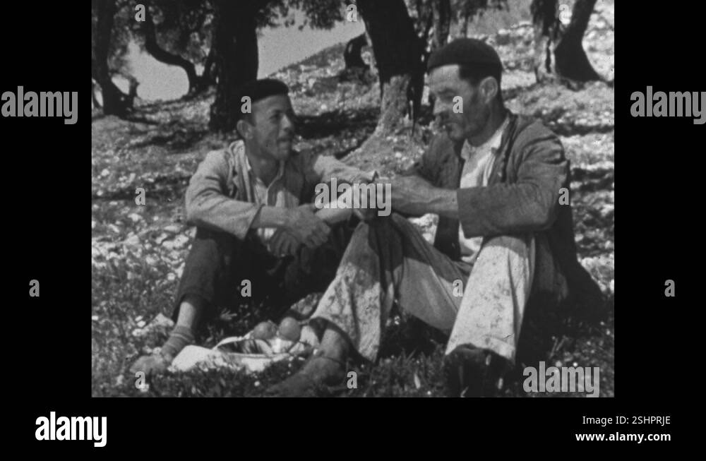 1950s: Man dips bread into olive oil with knife. Terraced hills. Men ...