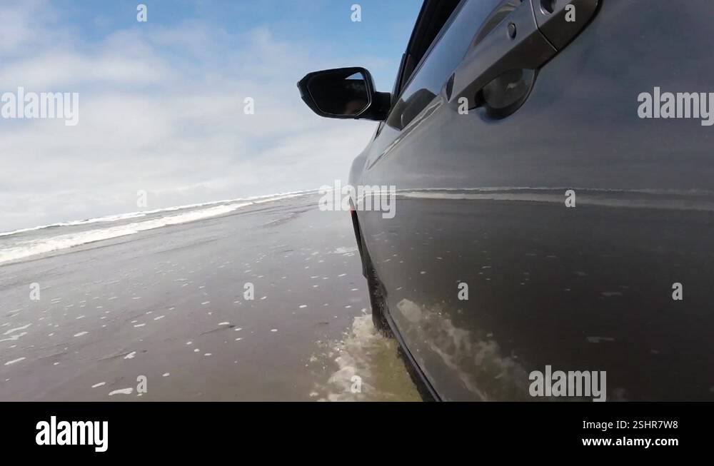 Gray car driving at the seaside. The car drives very close to the beach ...