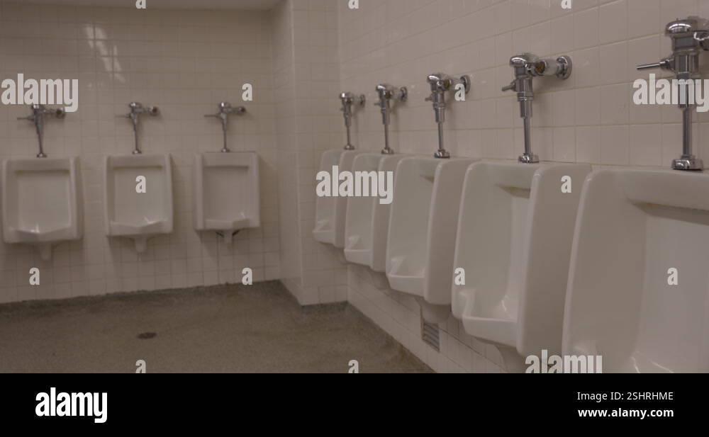 Urinals in public rest room washroom on white tile walls - empty ...