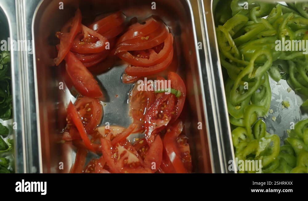 top view serving tongs take cut pieces of tomato from a metal tray to ...