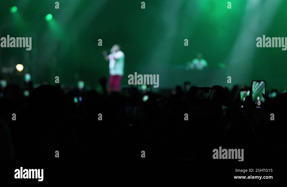 Singer and his band performing on bright scene in front of fans crowd ...