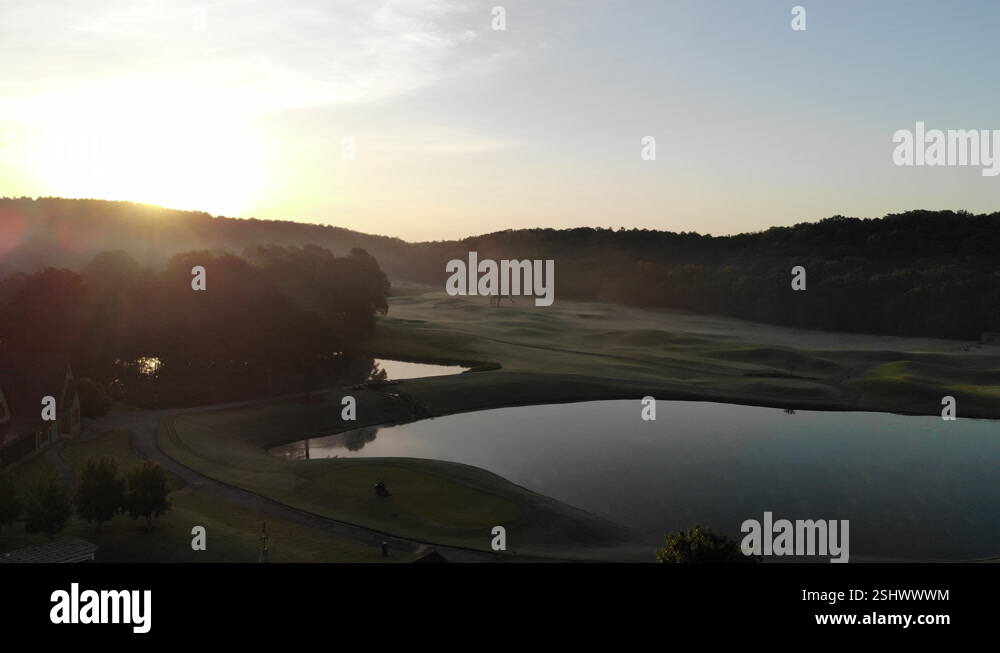 Sunrise aerial of golf course greenway with lake in the shot. 4K drone ...
