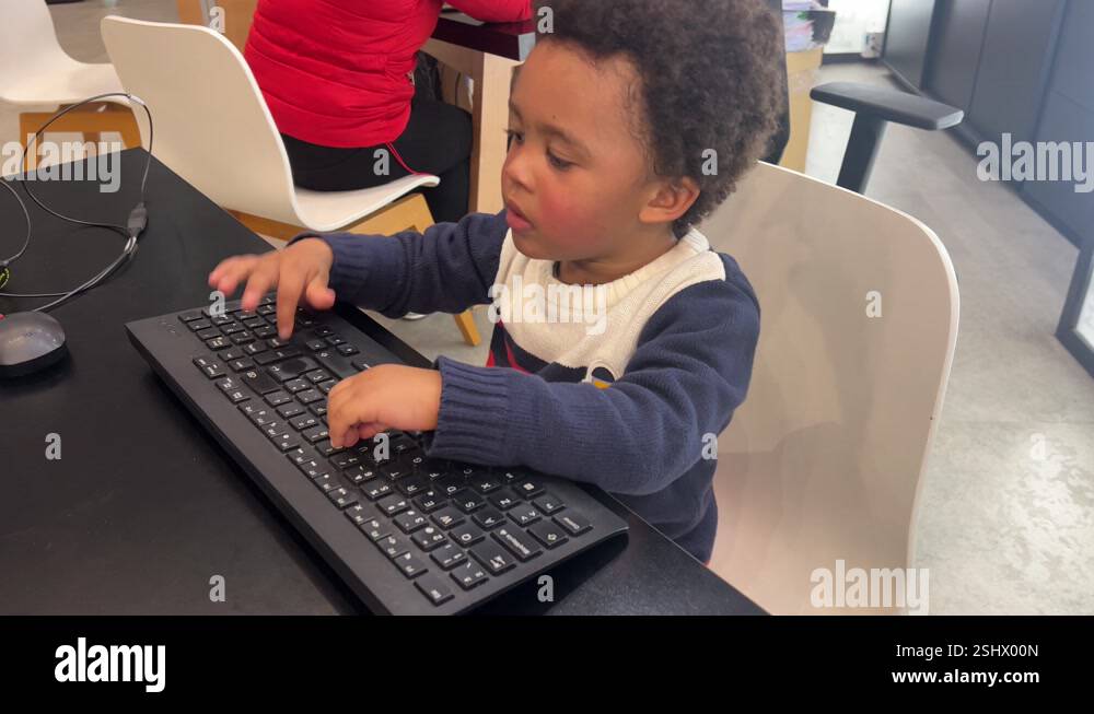 Expressive three-year-old black child mimics mother at office desk ...