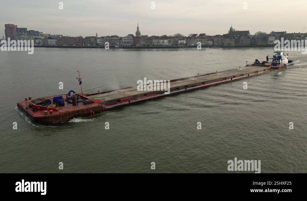 Empty cargo ship sailing on the river. In the background the city of ...