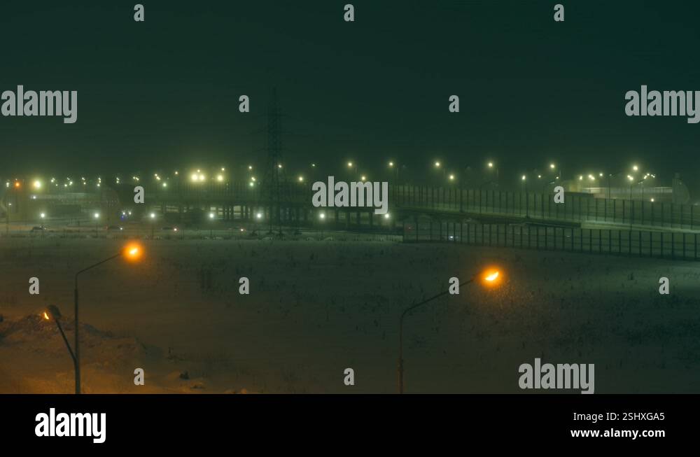 Night road in the fog from afar. Cars drive over the bridge in the ...