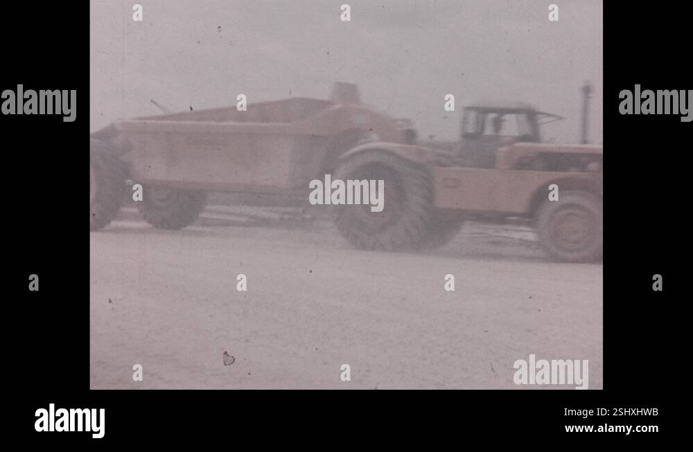 1950s: Steam shovel idle next to a sand pile. Dump truck drives around ...