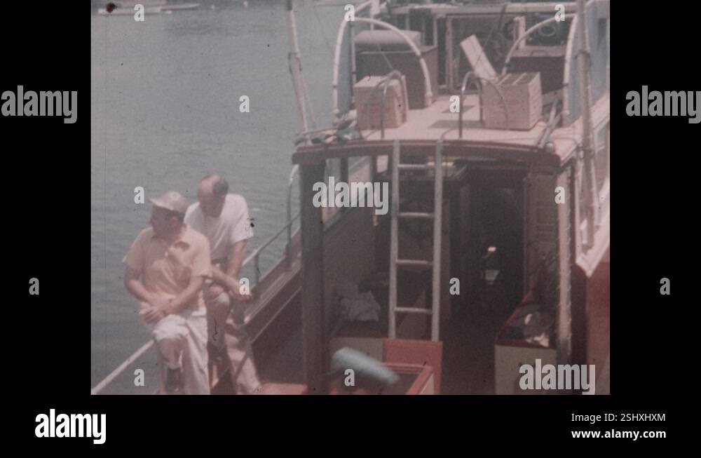 1950s: Fishermen shovel a catch from the deck of their boat. Man fills ...