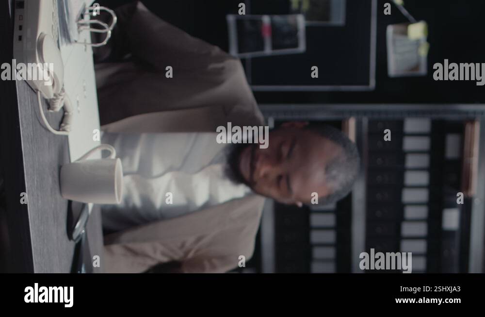 Vertical video: African american agent reading suspicious files in ...