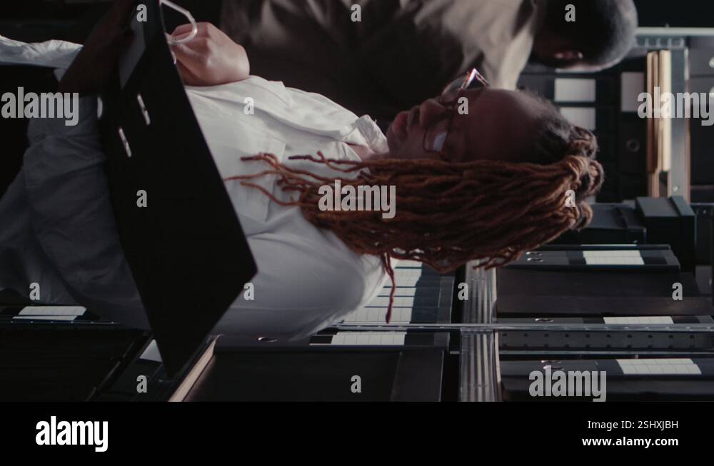 Vertical video: Police officers examining case files for clues in ...