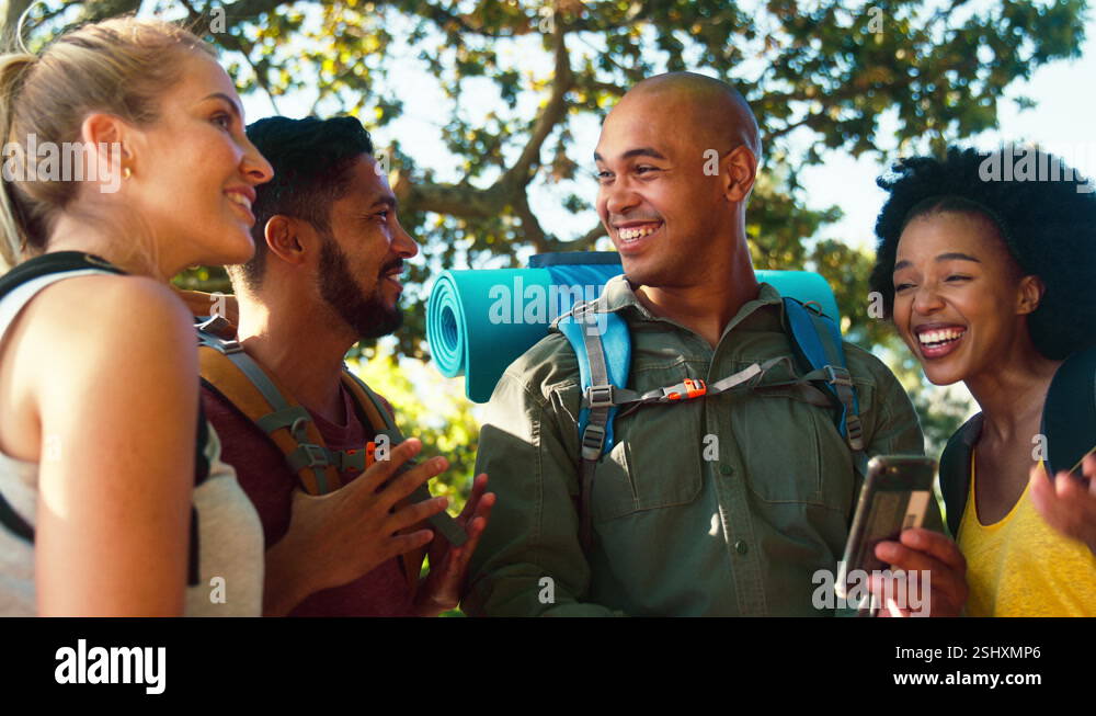 Group Of Lost Friends With Backpacks Using GPS On Mobile Phone On ...