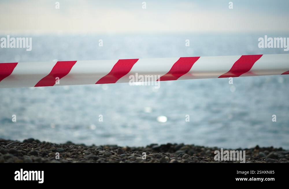 Red white warning tape barrier ribbon swinging in the wind across exotic sea Stock Video Footage ...