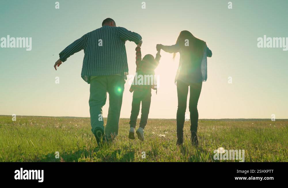Happy family is playing in park at sun, child holding hands is jumping ...