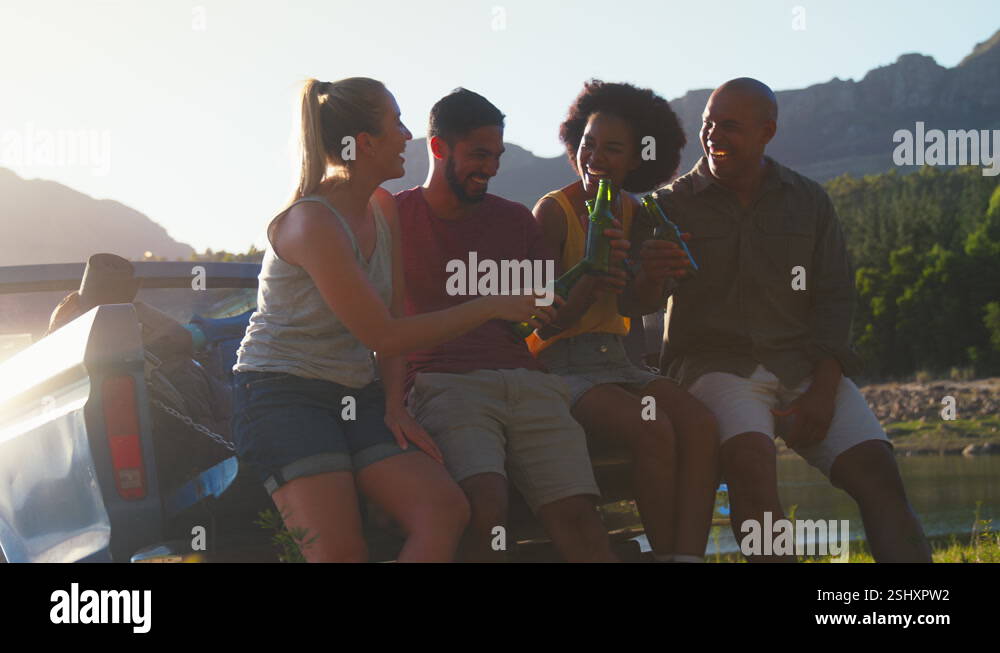 Friends With Backpacks Sitting On Tailgate Of Pick Up Truck On Road ...