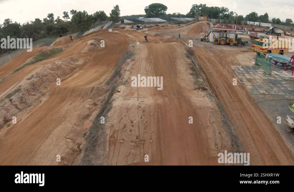 Motocross circuit with ramps, ups and downs of red dirt. Rider driving ...