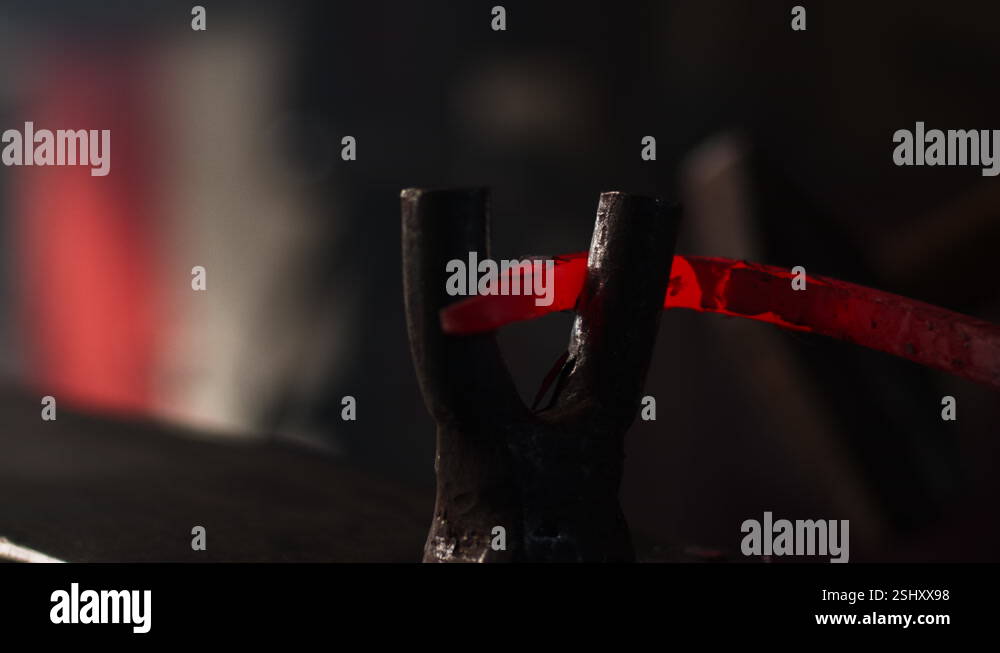 Blacksmith bends an iron rod through a vice grip on an anvil in a metal ...