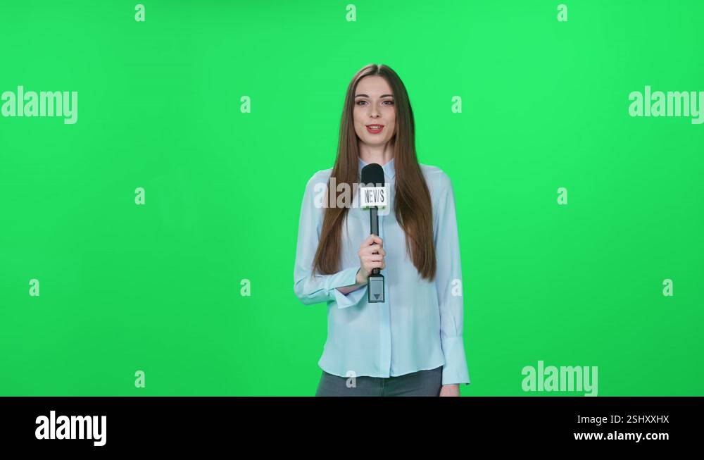 Young woman reporter looks into the camera and speaks, green background ...