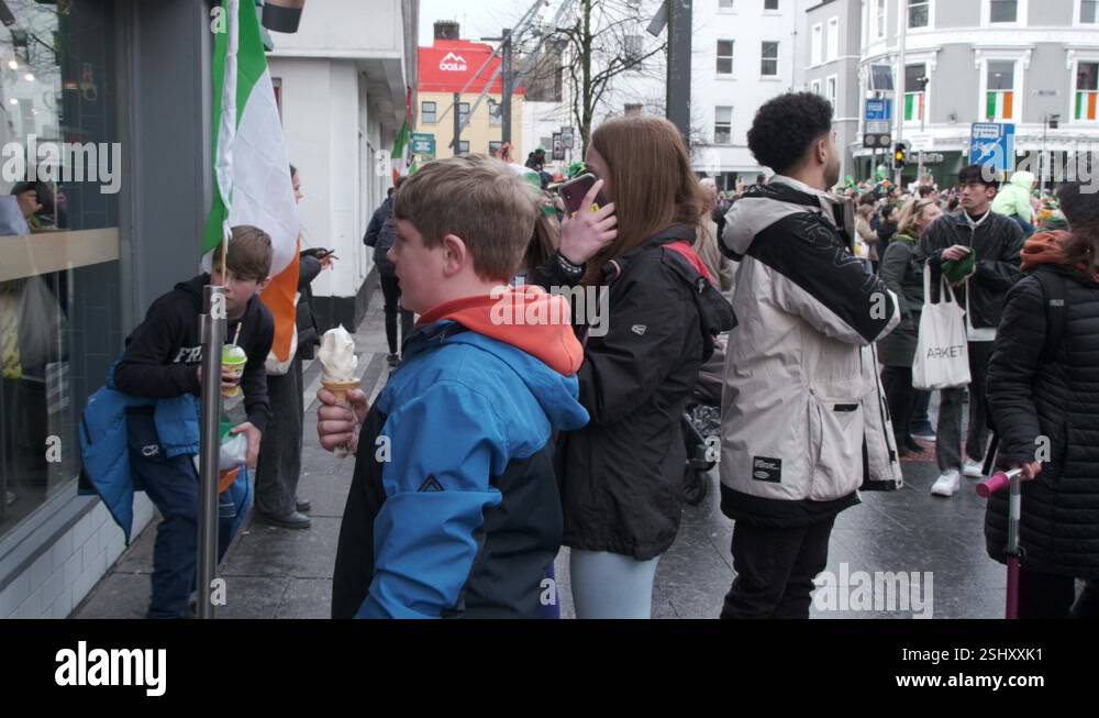 Irish flag and group of teenagers with crowd filling street in Cork ...
