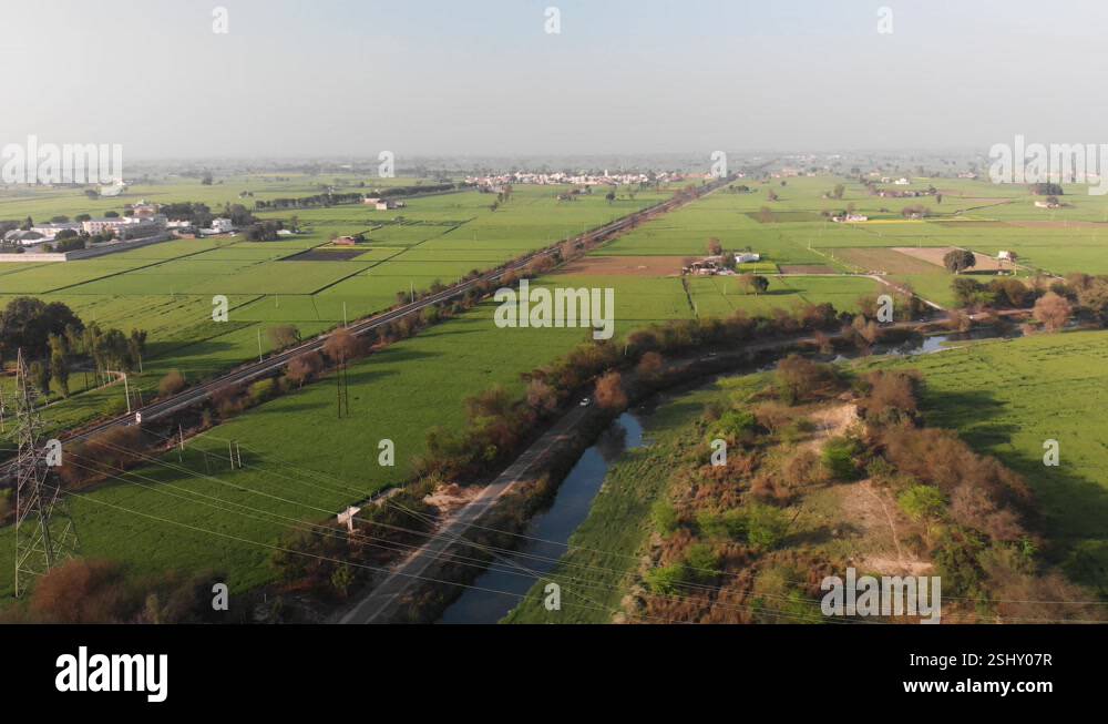 A water stream, road and railway track crossing thought the green Stock ...