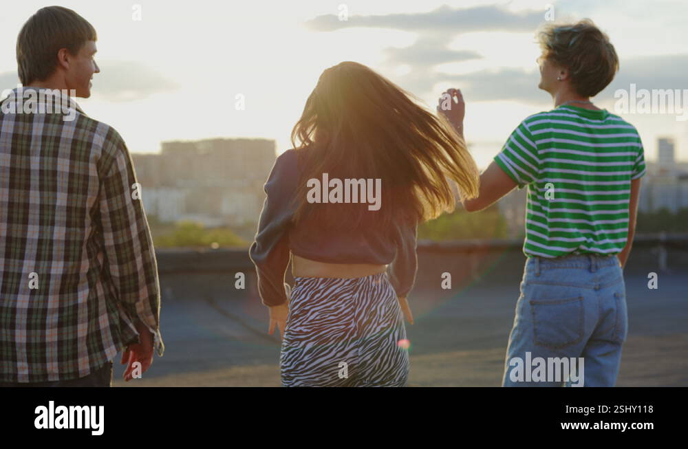 Rooftop party. Back view of the three caucasian friends walking in the ...