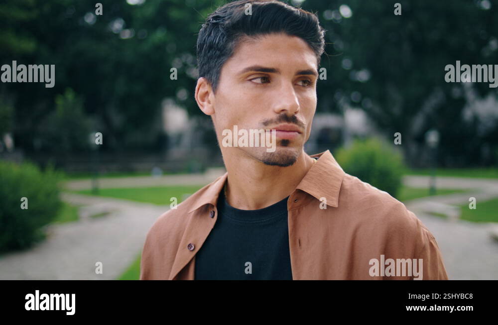 Serious guy posing park portrait. Young man face looking camera ...