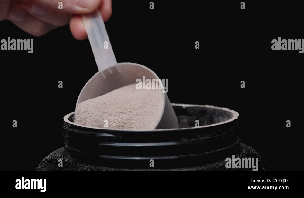 I pour the sports nutrition powder into a jar on a black background ...